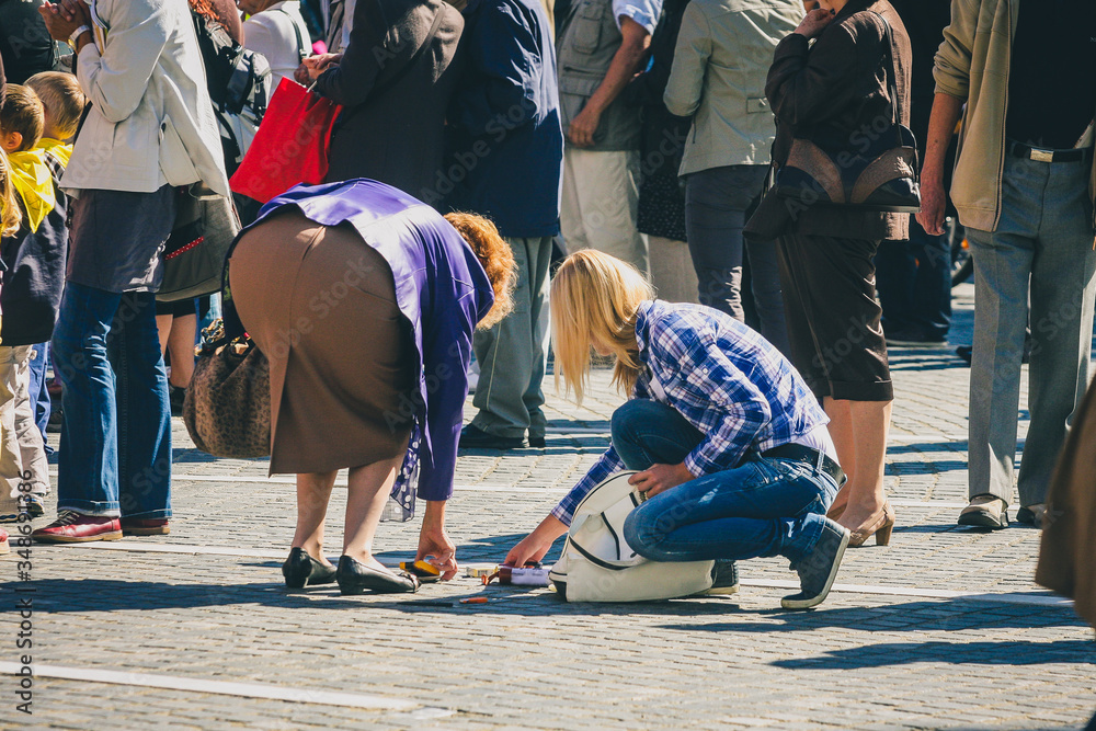 Older woman helping to pick up contents of purse or a bag of a young ...