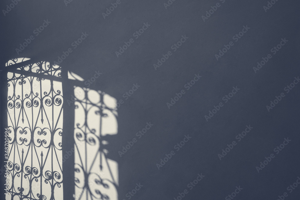 Iron forged grate fence gate contrast shadow on the wall in the morning ...