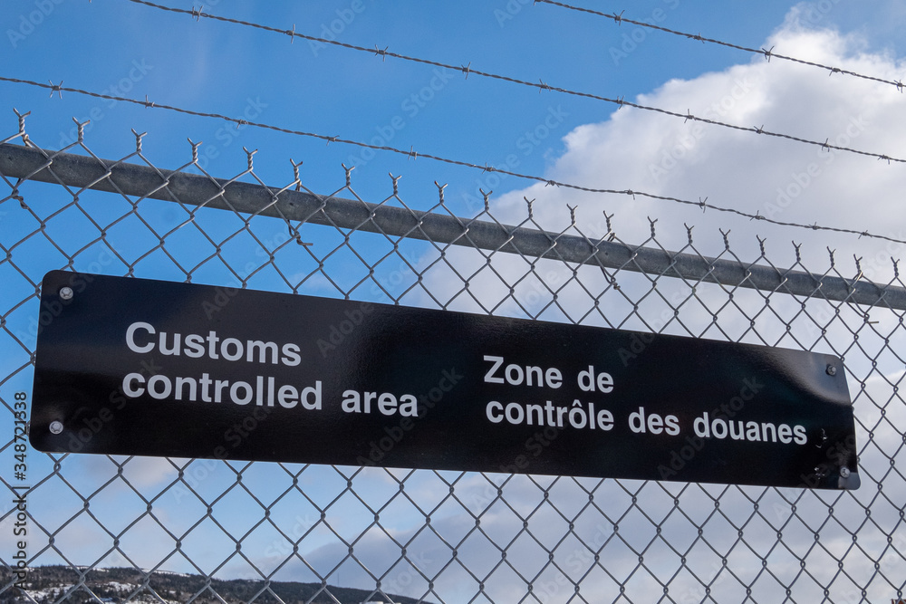 Black sign with white letters spelling customs controlled area. The ...