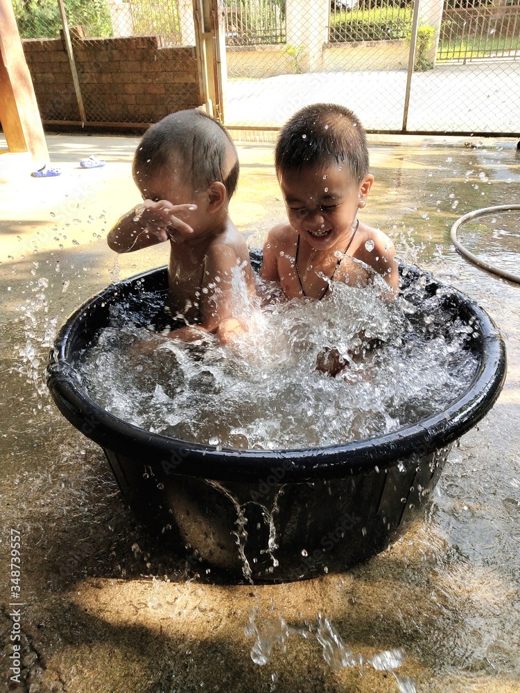 Children Playing With Water In Container Stock Photo | Adobe Stock