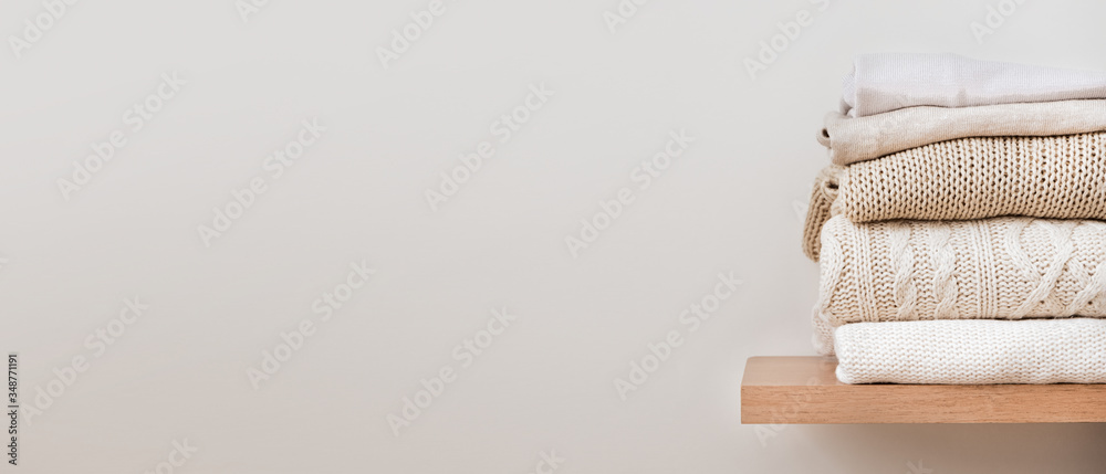A stack of neatly folded warm knitwear, wool on a wooden shelf and a ...
