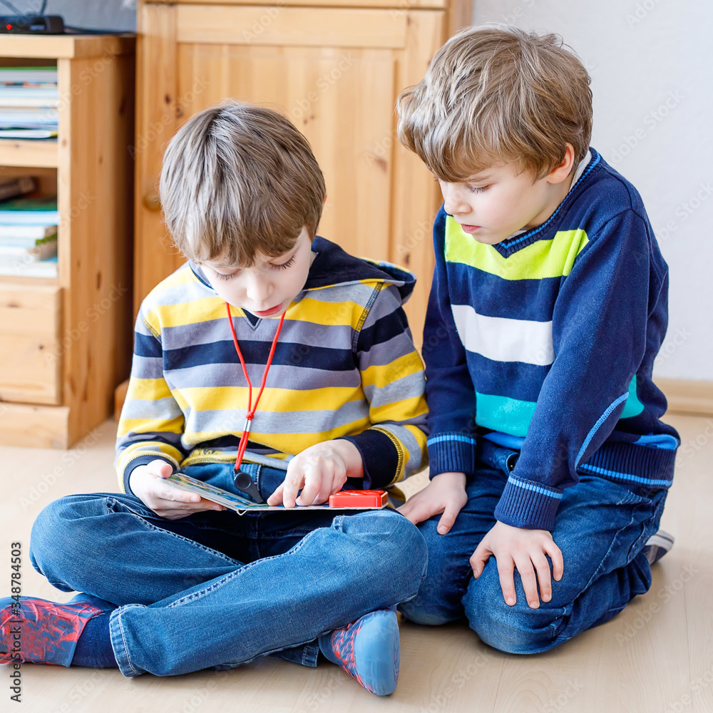 Two little kid boys reading a book at home. Older schoolboy reading for ...