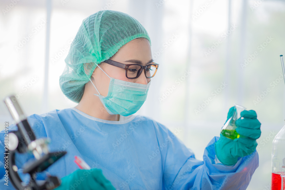 Asian Young woman scientist looking through a microscope in a ...