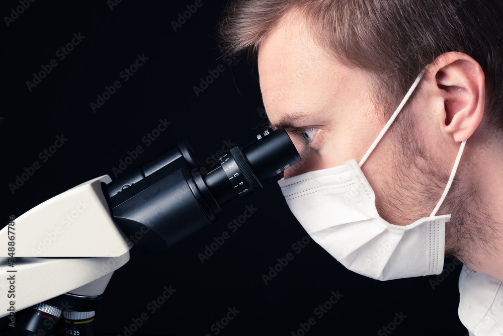 Up-close profile of white male scientist using binocular microscope ...
