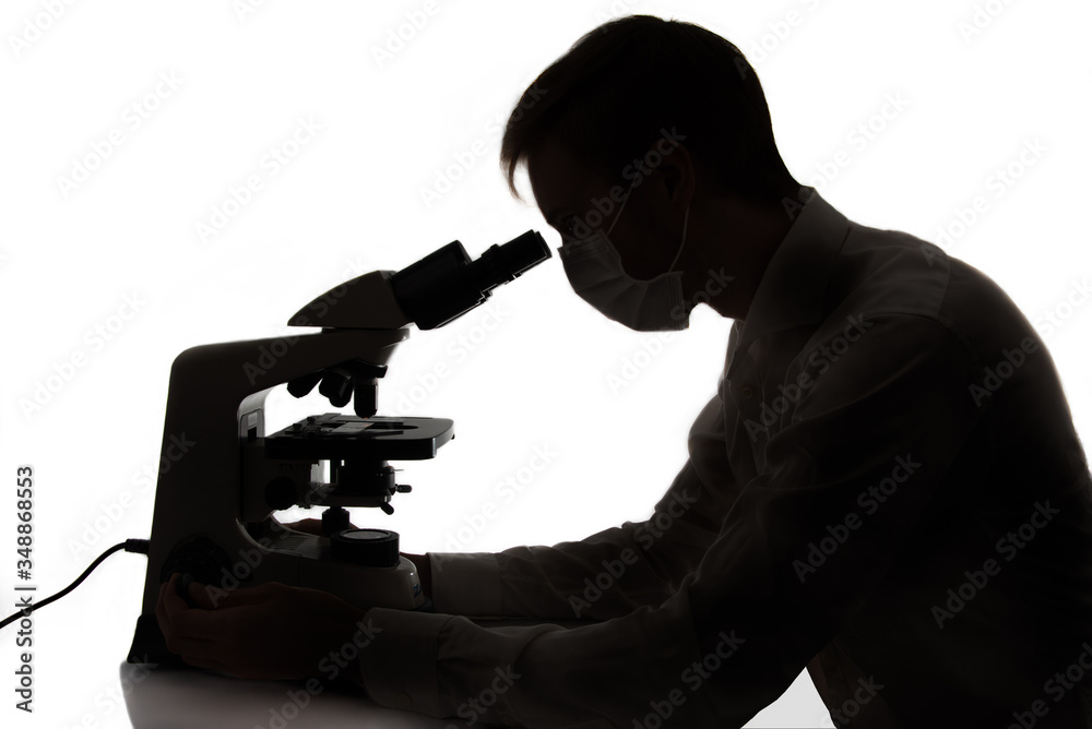 Silhouette of a white male scientist using a binocular microscope ...
