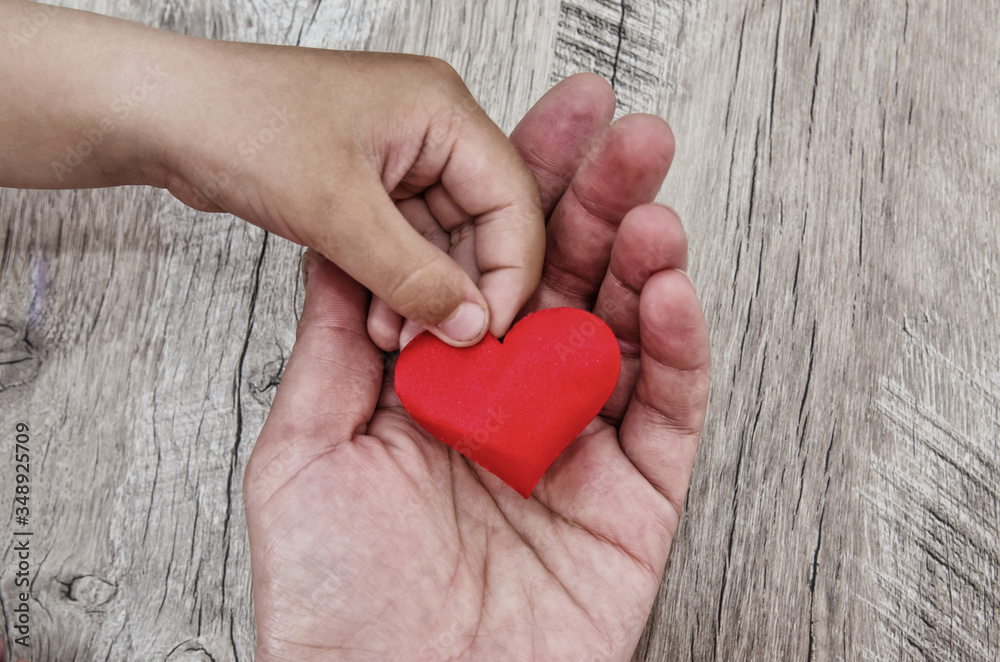 One hand puts a red heart shape in another hand, love and compassion ...