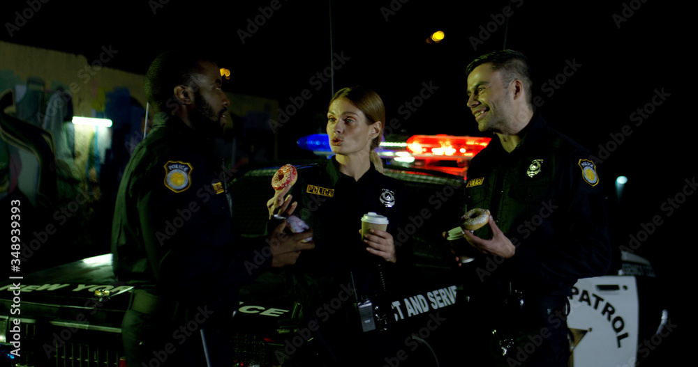 Mixed-races male and female police officers talking cheerfully and ...