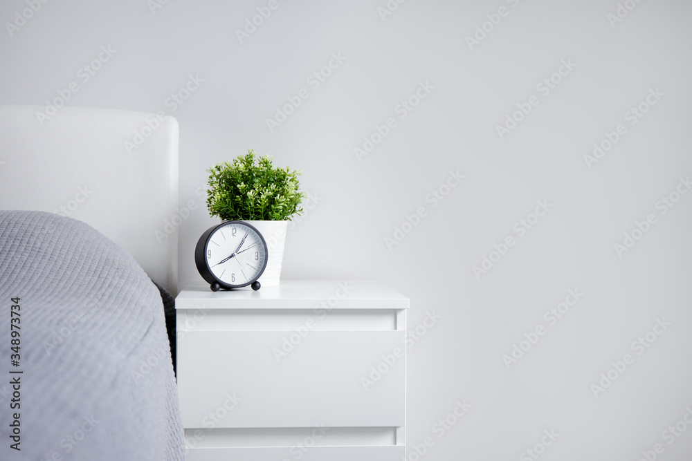 good morning concept - alarm clock and houseplant on bedside table and ...