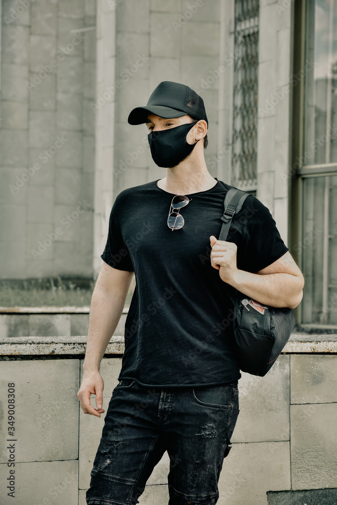 Attractive male policeman security guard in a black medical mask keeps ...