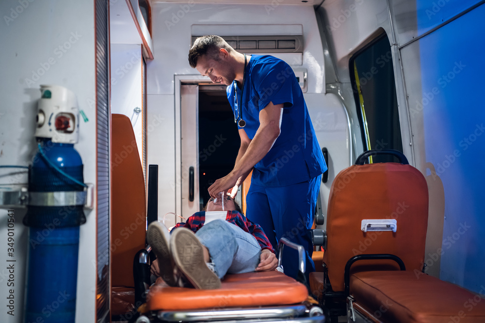 Young paramedic giving an oxygen mask to his female patient in an ...