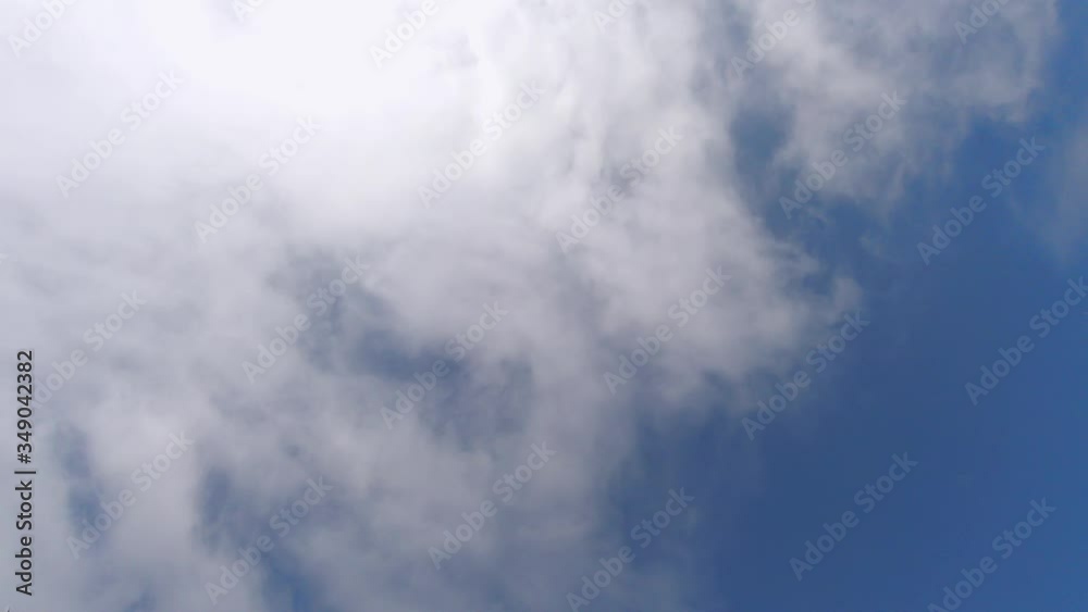 Fast moving white clouds in a blue sky scudding across the frame to ...