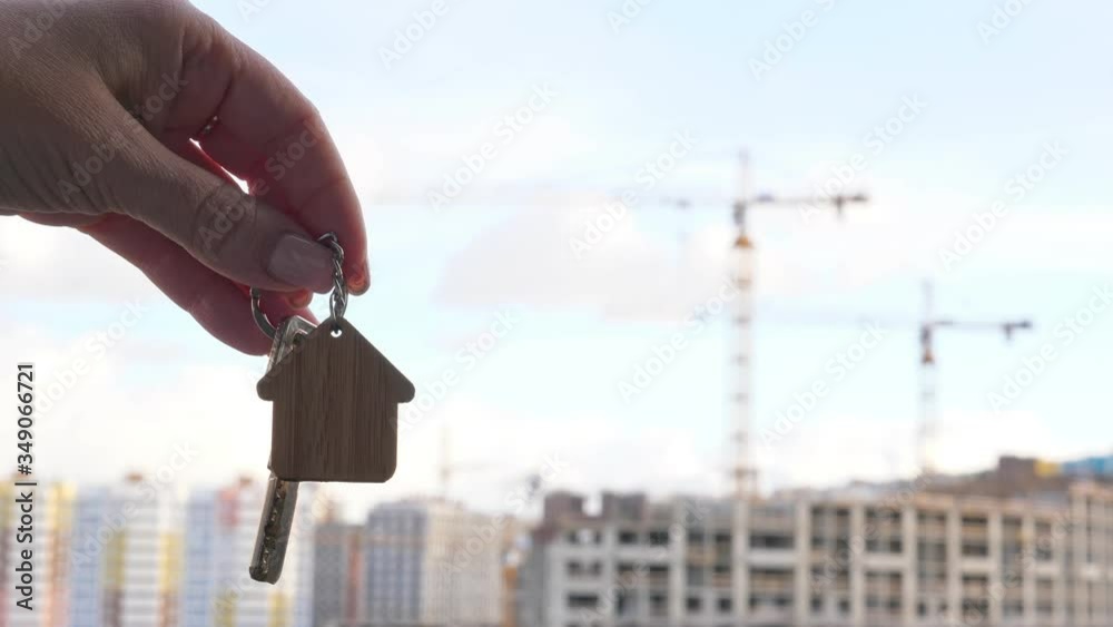 Key with house keychain in hand on background with new high-rises ...