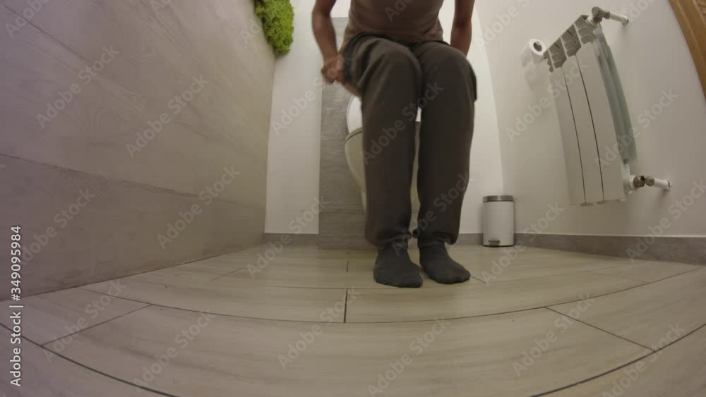 Woman peeing using toilet bowl wearing home clothes. Low angle shot of ...