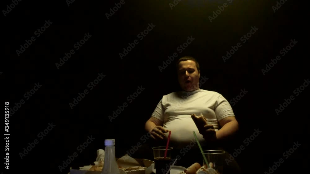 Stockvideo Fat man eating junk food burgers and hot dogs and watching ...
