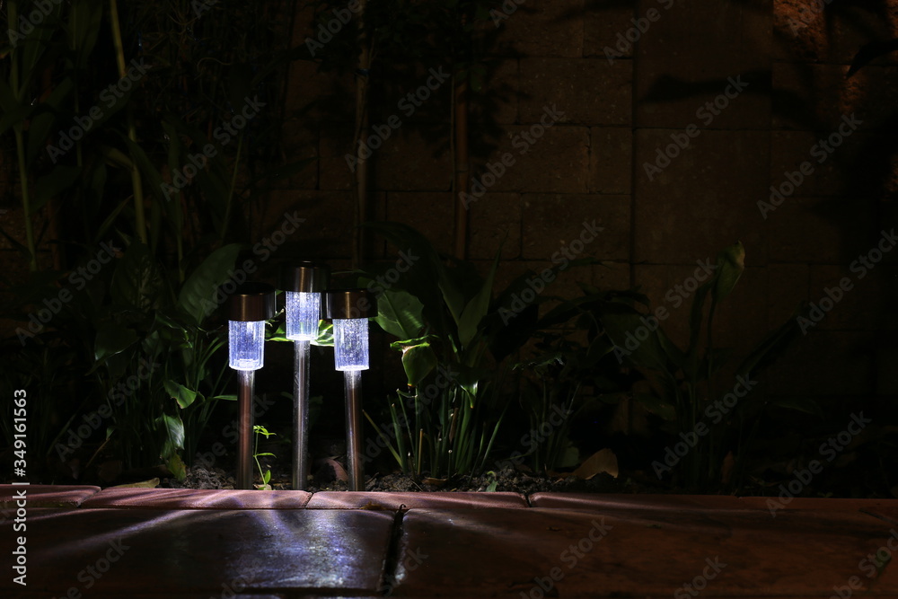 Garden LED lamp lighting. Small solar lighting shining in a garden and ...