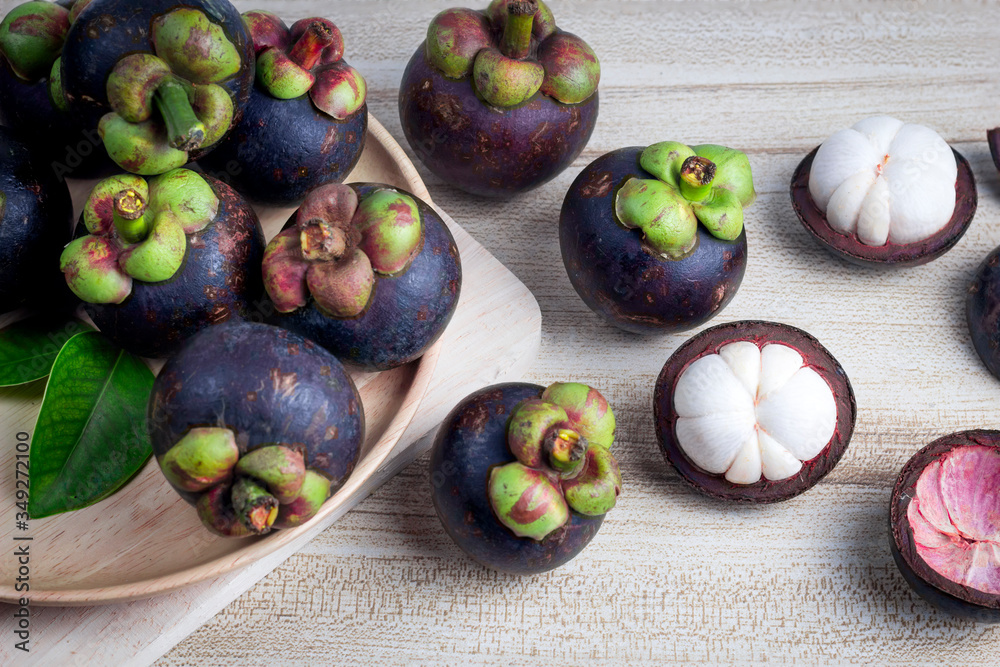 Mangosteen and cross section showing the thick purple skin and white ...