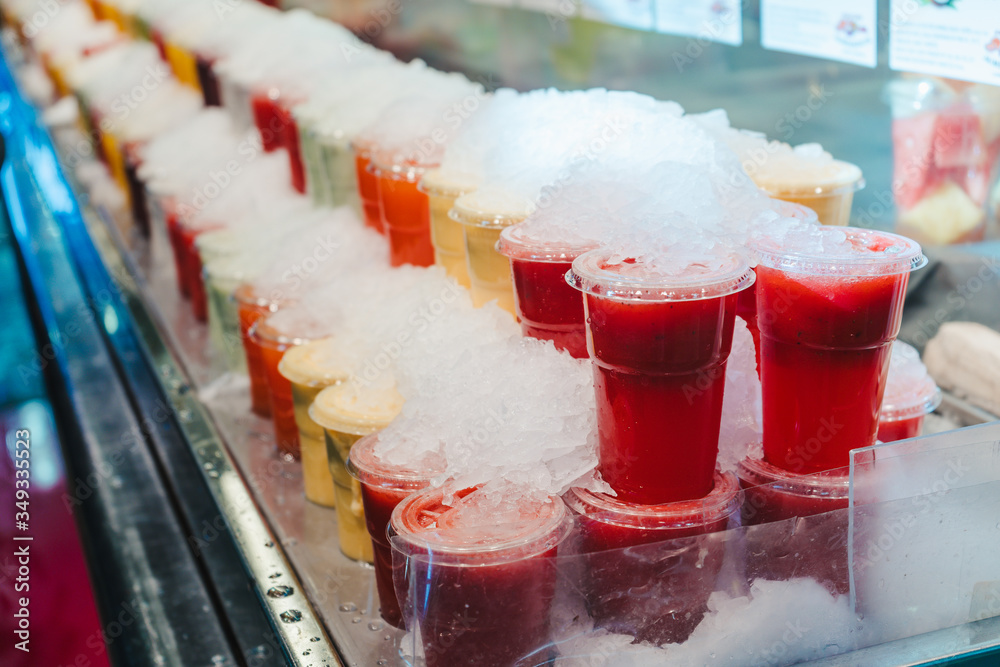 Fruit juice mix with ice arranged in plastic cups on a market stall ...