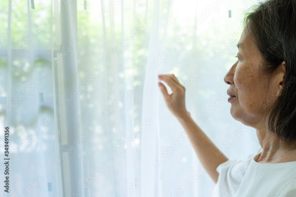 Senior lonely asian woman with sad face looking out of the window from ...