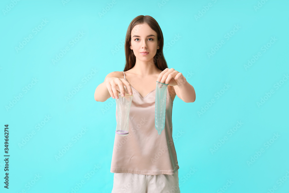 Young woman with male and female condoms on color background Stock ...