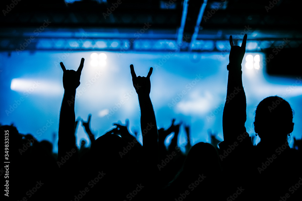 Fans showing signs of the horns during a rock band concert in a club. A ...