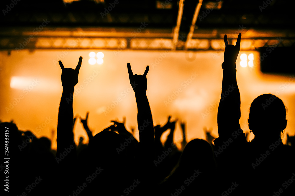 Devil horns hand. Fans showing signs of the horns during a rock band concert in a club. A crowd ...