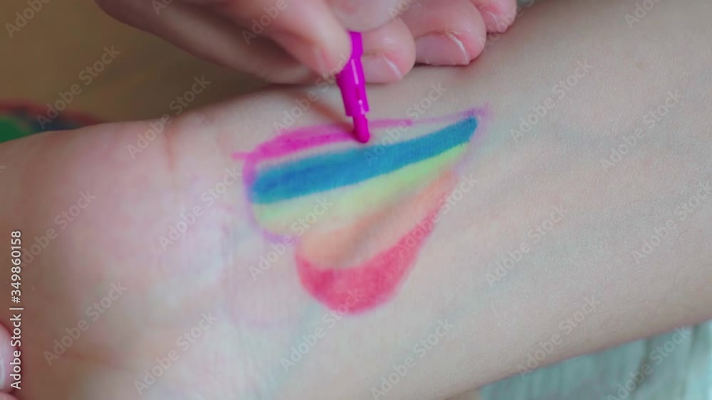 Pride day. Female drawing a rainbow flag on her hand wrist. LGBTQ style ...