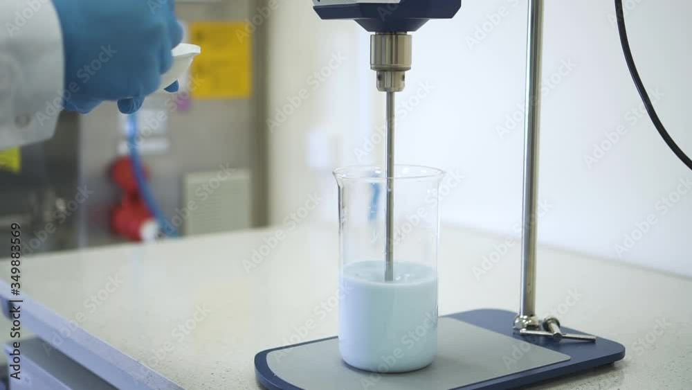 chemist hand add pour powder to liquid reagent in chemical mixing ...