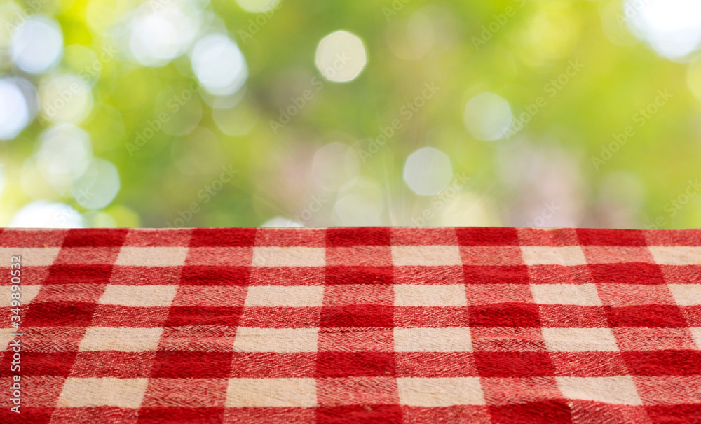 Red checkered tablecloth texture top view with abstract green bokeh ...