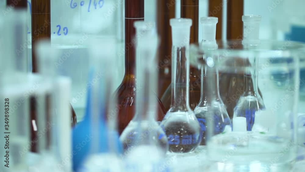 Row of flasks with transparent liquid in lab. Spbd Camera moving along ...