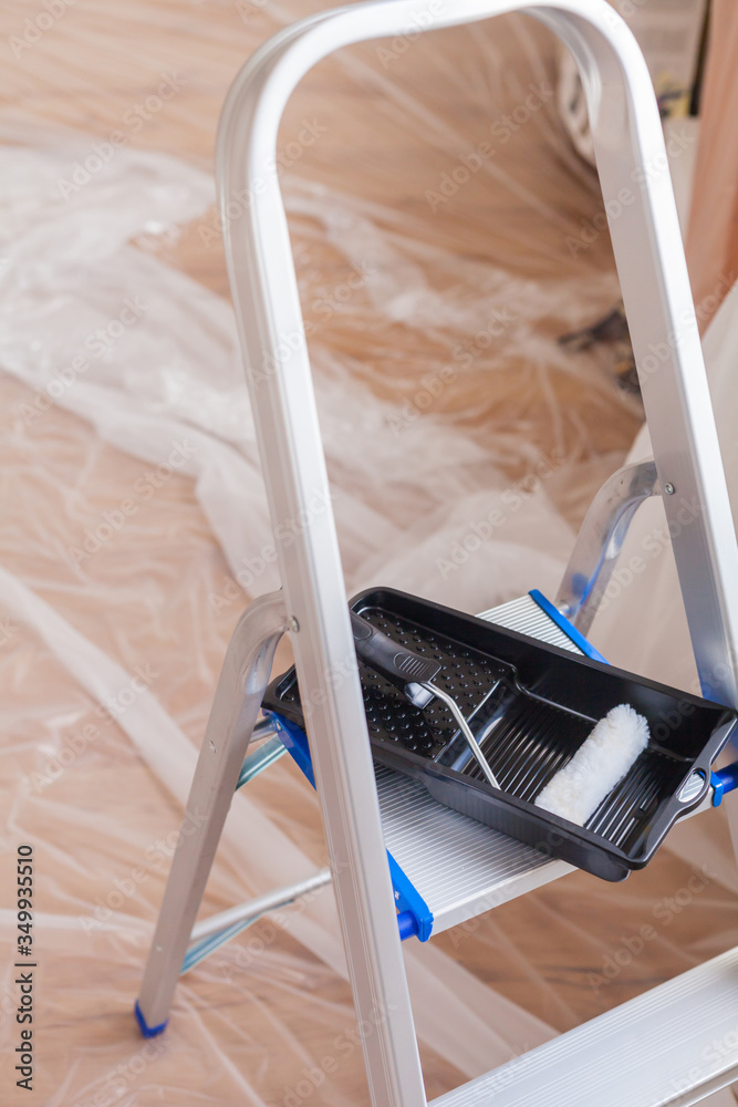 Aluminum ladder is folded out on the taped floor with drip tray ...