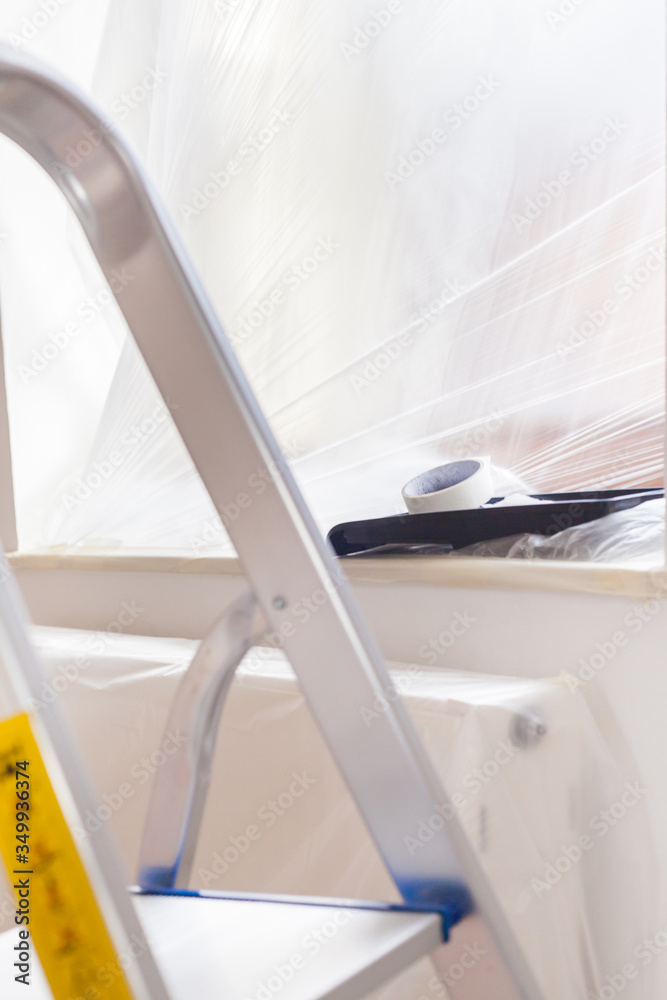 Aluminum ladder is folded out on the taped floor with drip tray ...