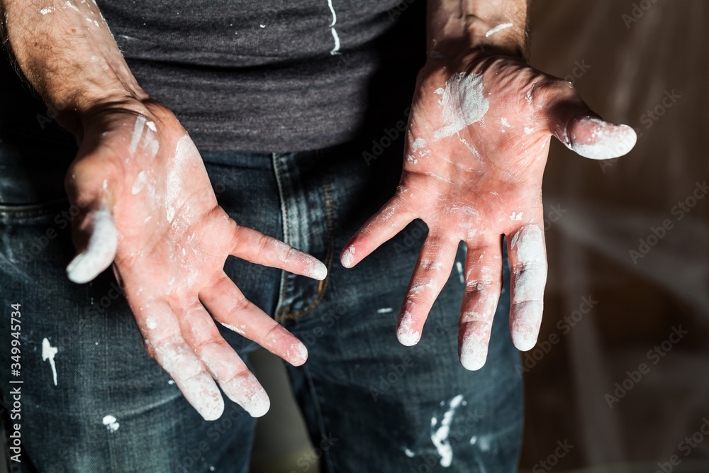 Craftsman with white paint particle at hands and clothes after painting ...