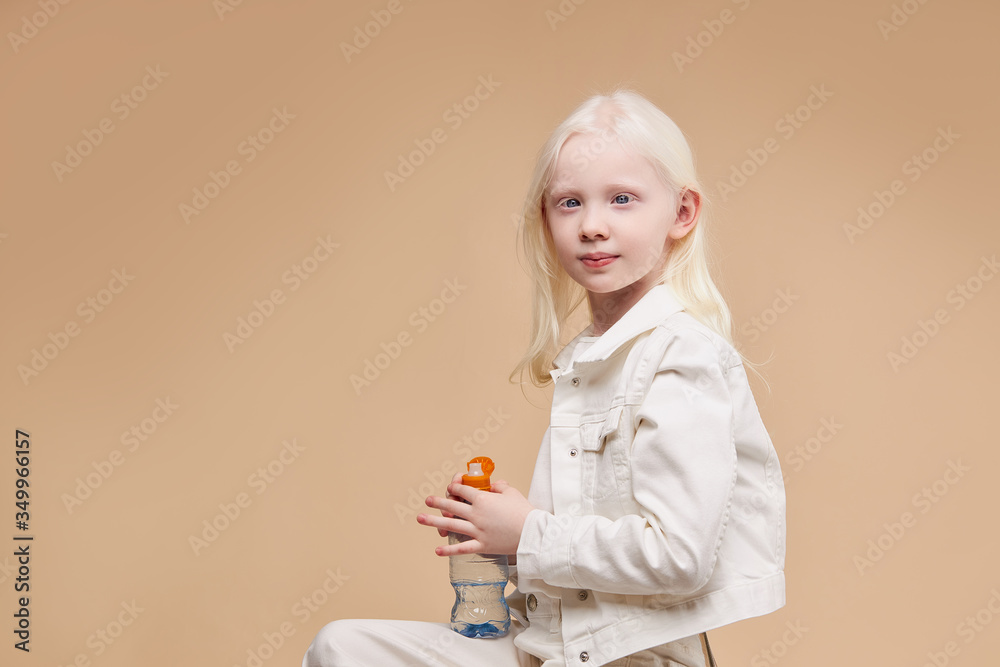 side view on gorgeous calm and shy albino child sitting with water ...