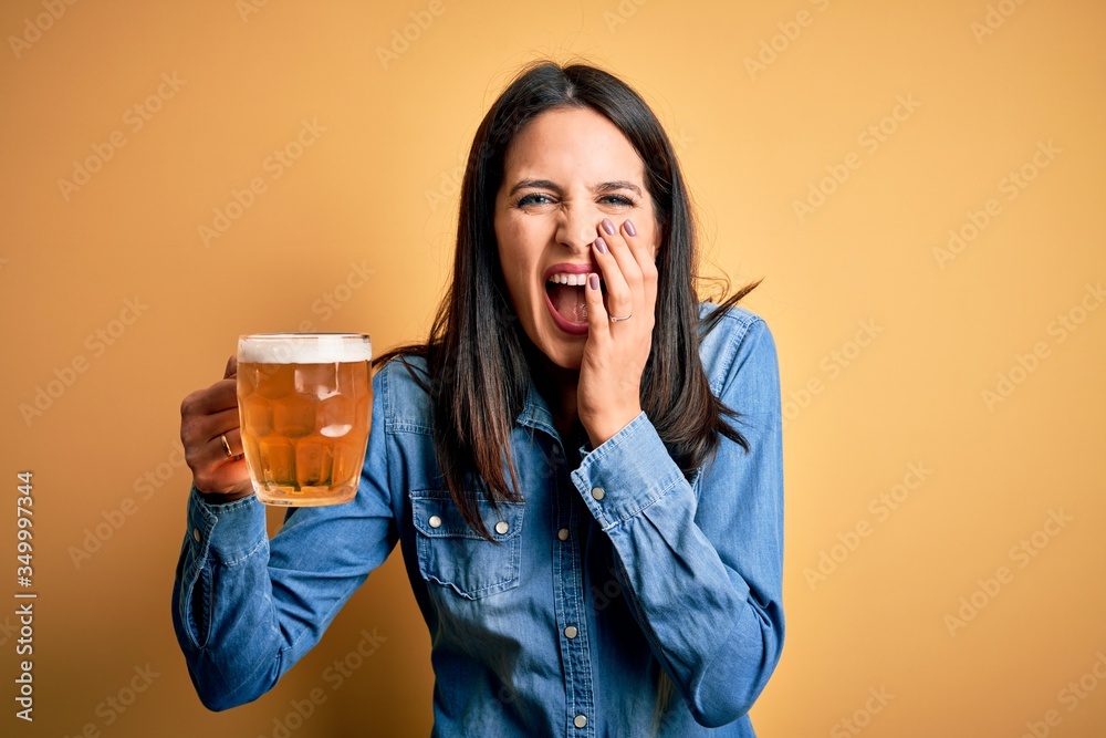 Young woman with blue eyes drinking jar of beer standing over isolated ...