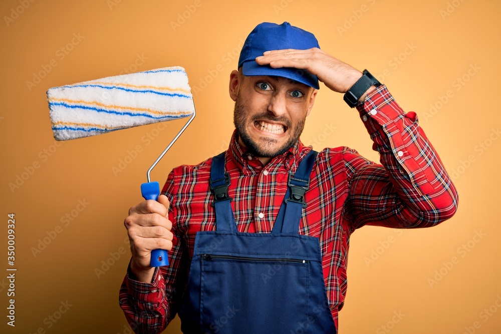 Young handsome painter man painting wall using roller over isolated ...