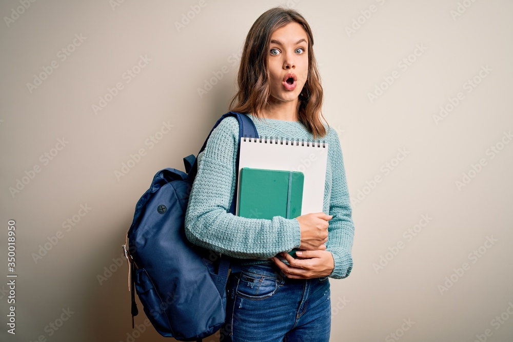 Young blonde student girl wearing backpack and books from school over ...