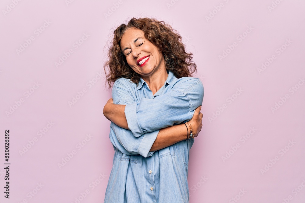 Middle age beautiful woman wearing casual denim shirt standing over ...