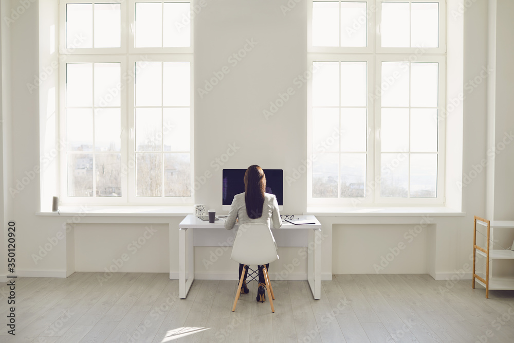 White bright spacious office. Back view of a female employee working at ...