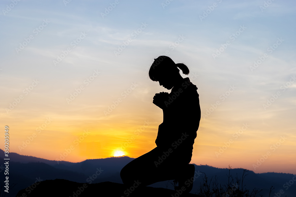 Silhouette of human kneeling down praying to the God at sunset ...