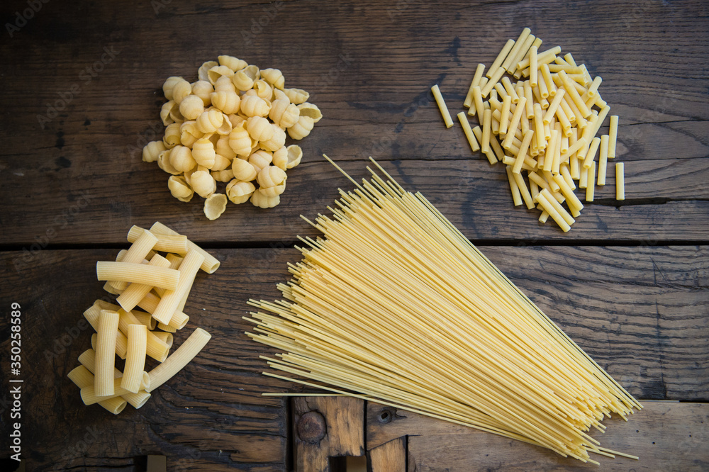 dried Italian pasta on an old brown wooden table with a cutting light ...
