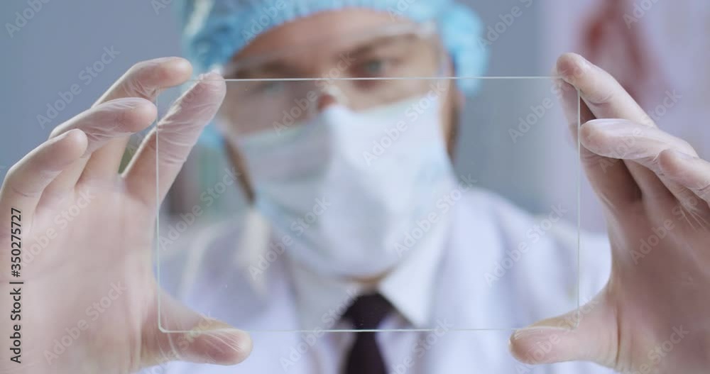 Close-up portrait of blue-eyed male scientist using glass tablet ...
