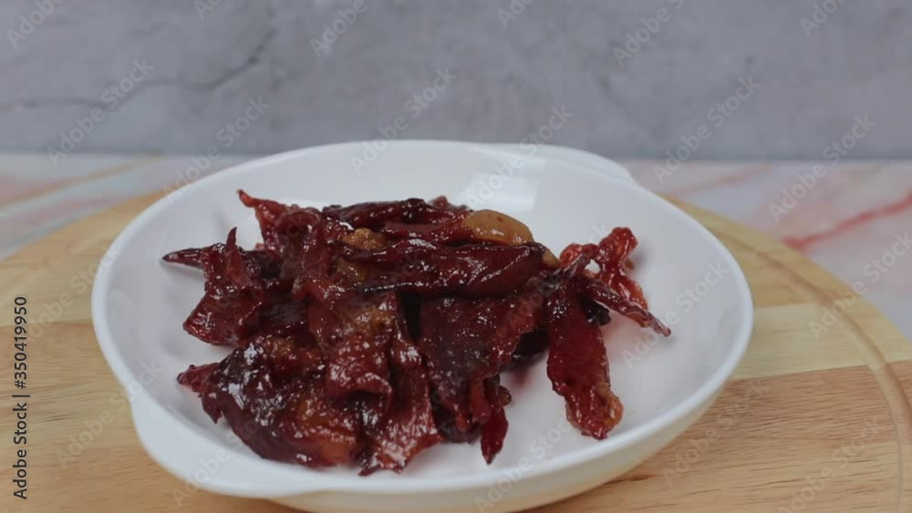 sliced sheets of dried and crispy pork on a white plate on a wooden ...