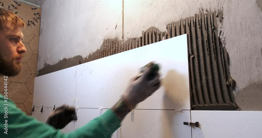 Tiler cleans with rag ceramic tile just laid on wall, gently rinses ...