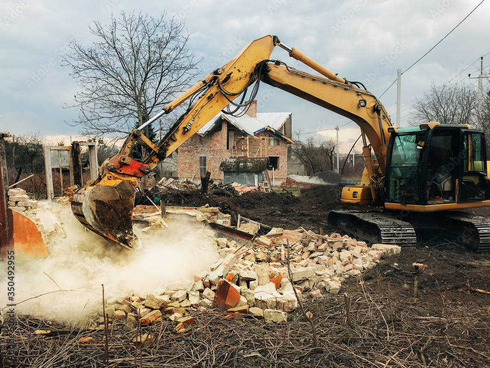 House crushing and collapse. Excavator destroying brick house on land ...