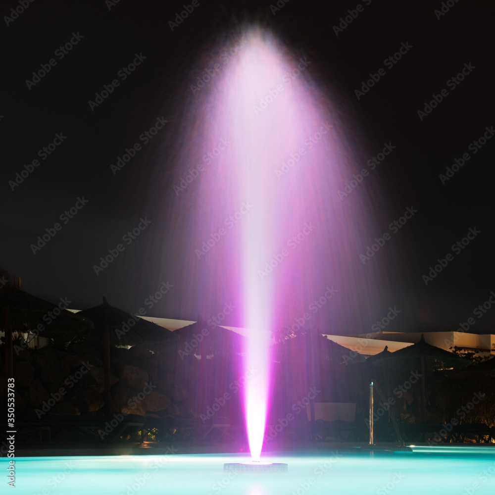 Blurred (long exposure) bright neon purple sprinkling water fountain ...