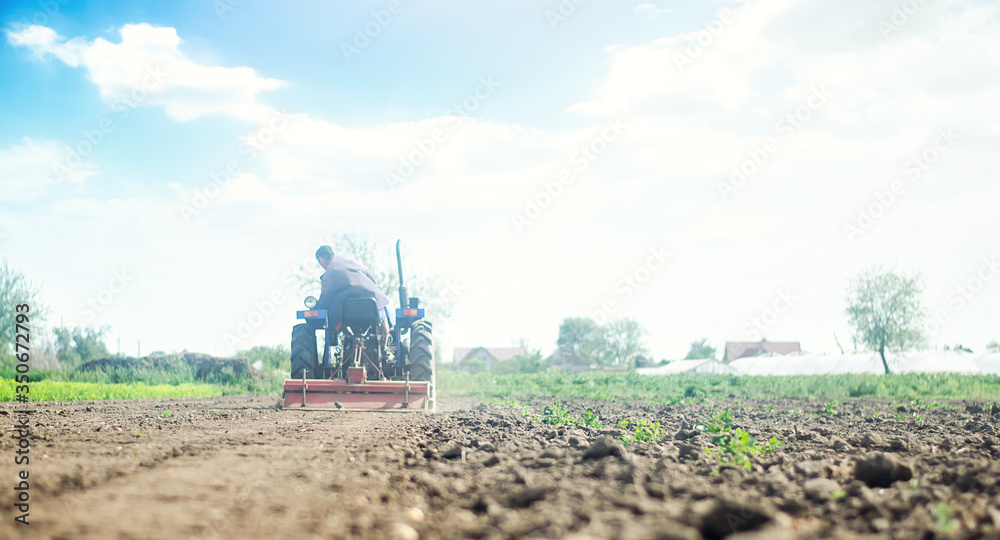Farmer on a tractor with milling machine loosens, grinds and mixes soil ...