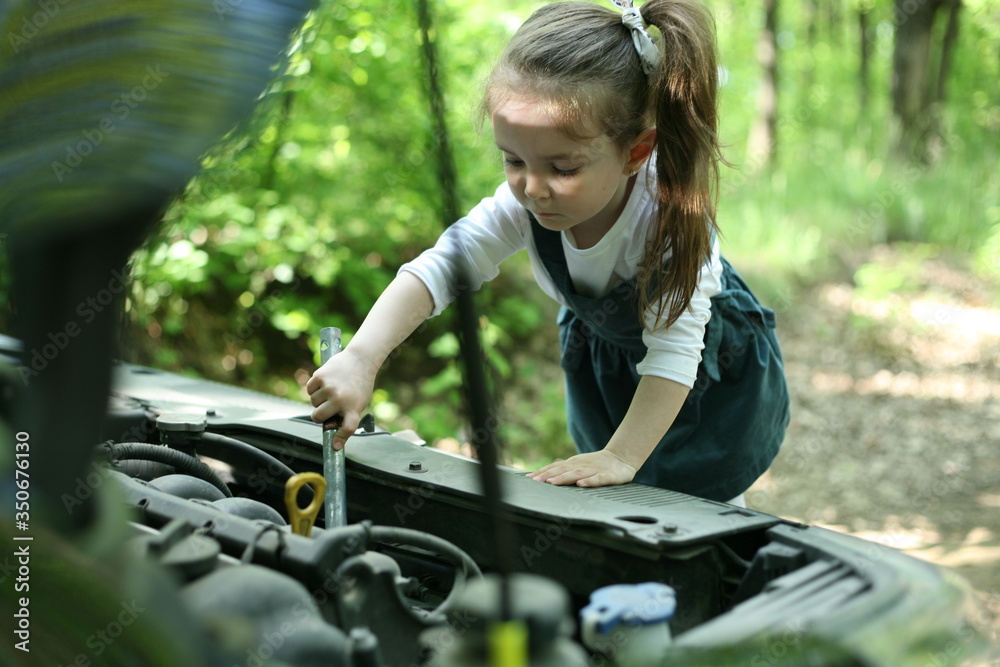 Little girl is repairing a car. The child behaves like an adult. Little ...