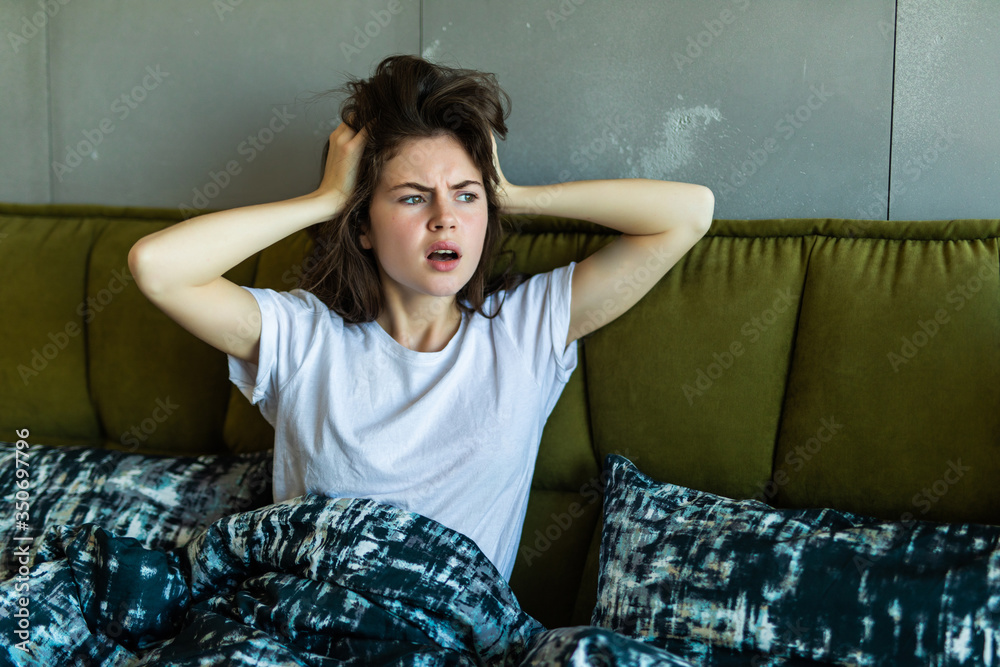 Amazed beautiful young woman wake up in bed with shocked face emotion ...