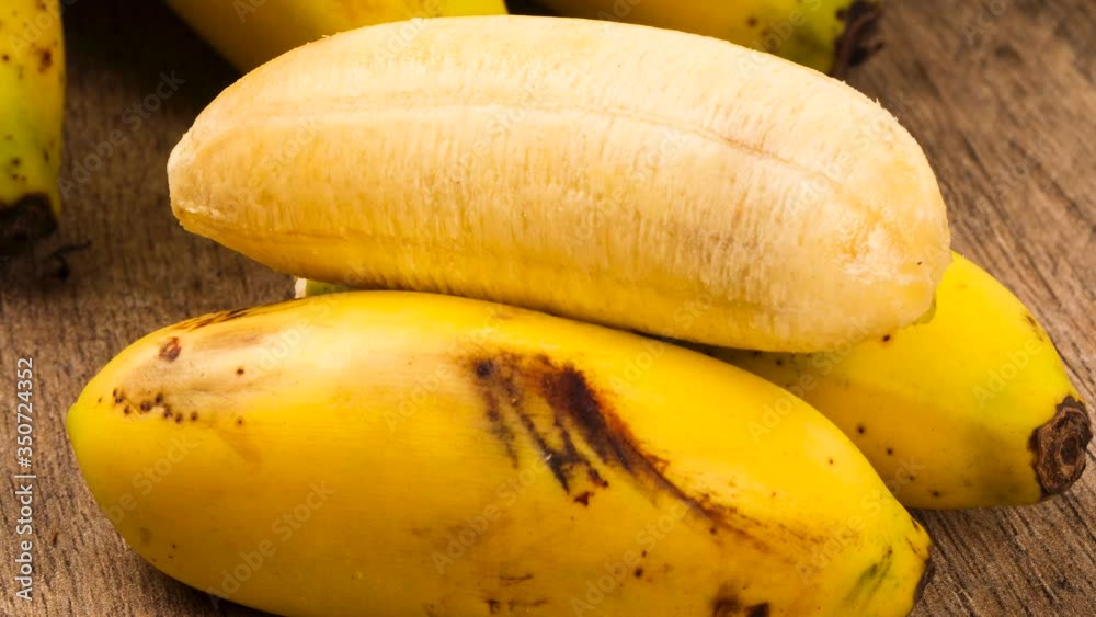 Two bunches of bananas and a sliced banana in a pot over a table. Stock ...