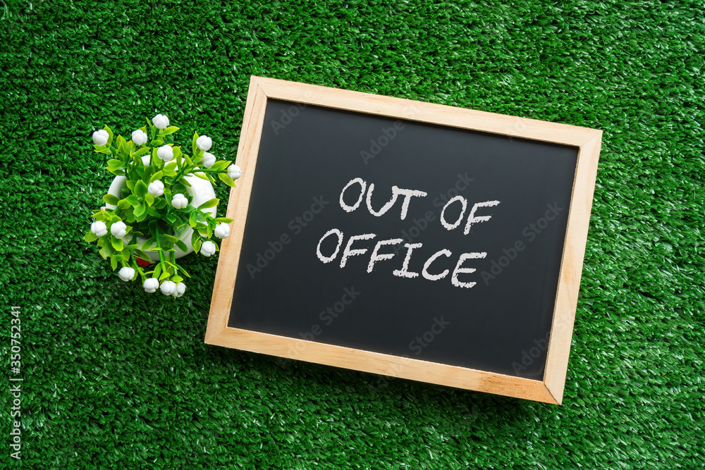 OUT OF OFFICE text in white chalk handwriting on a blackboard with ...